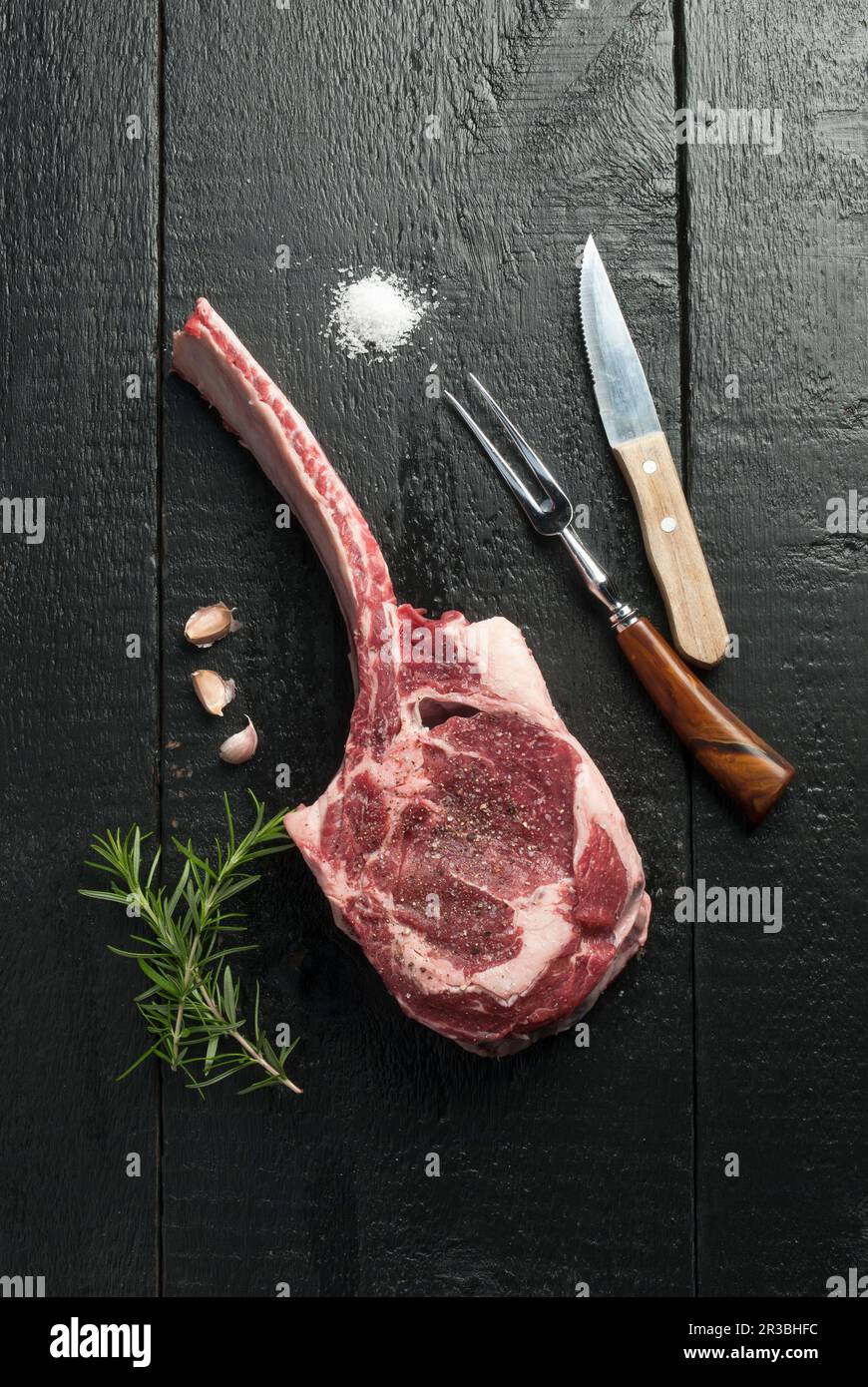 Raw tomahawk steak with rosemary and garlic Stock Photo - Alamy