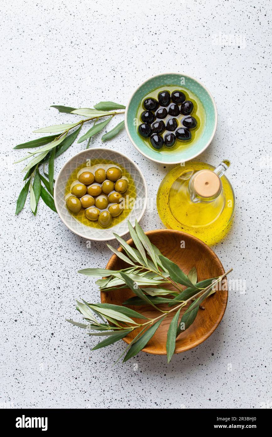 Green and black olives with olive oil in a glass bottle, olive tree ...