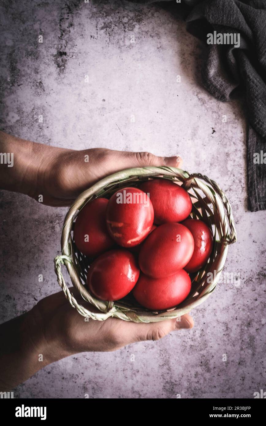 Hands holding basket with red eggs Stock Photo - Alamy