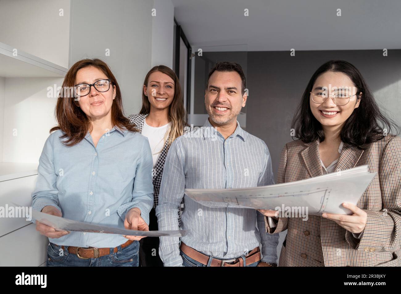 Confident business people standing in office holding architectural ...