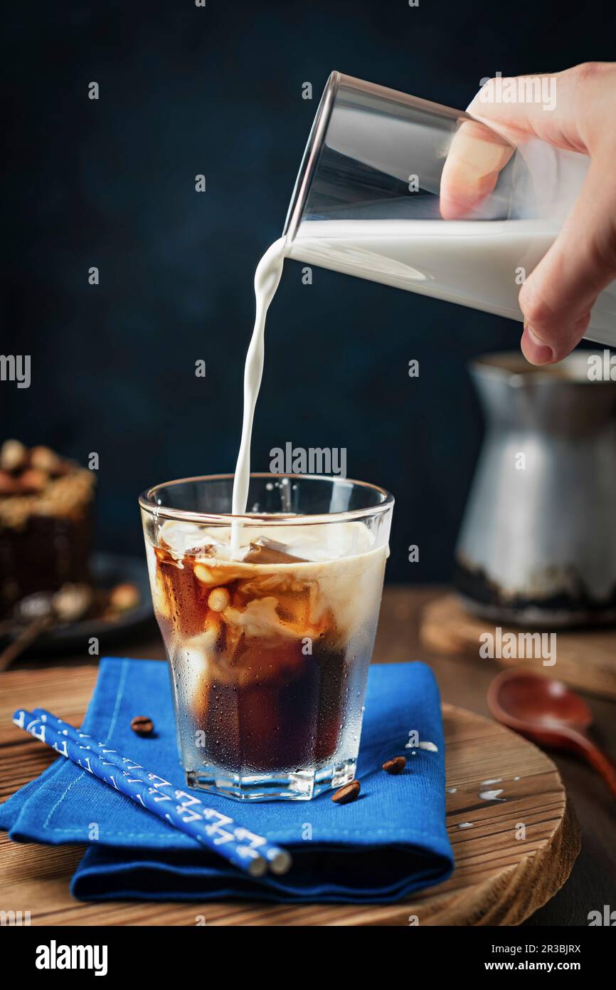 Ice cold coffee with a hand pouring milk Stock Photo - Alamy