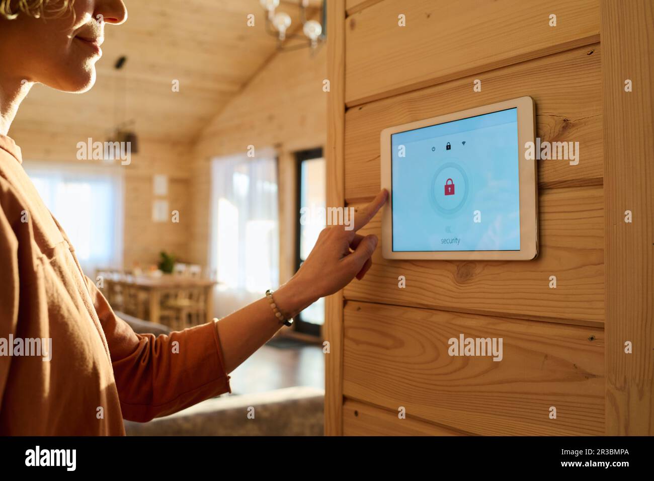 Hand of young woman on panel of alarm system with lock sign on screen ...