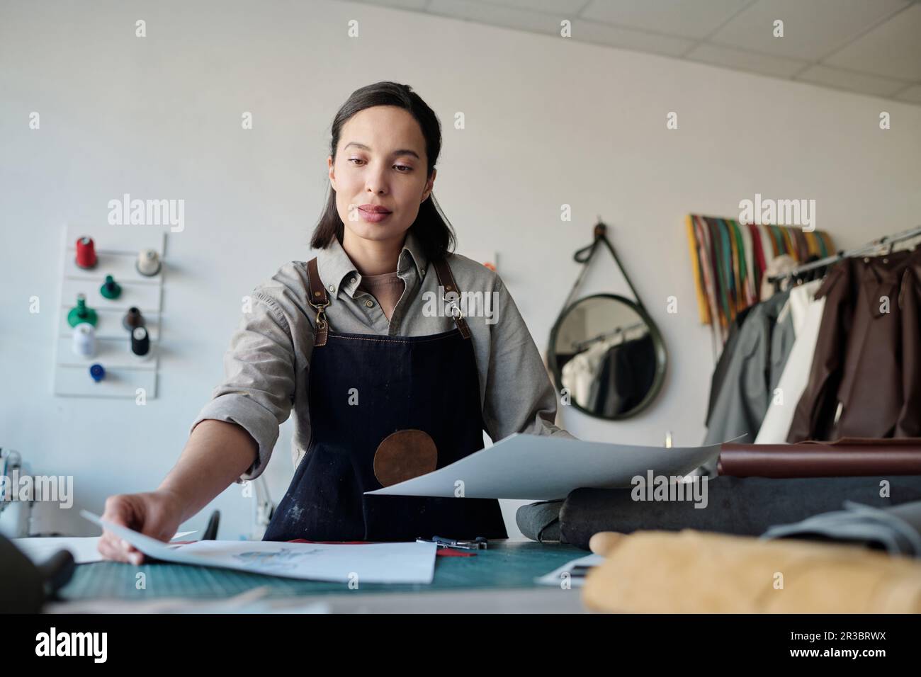 Female leatherworker or tailor choosing sketches with new models of ...