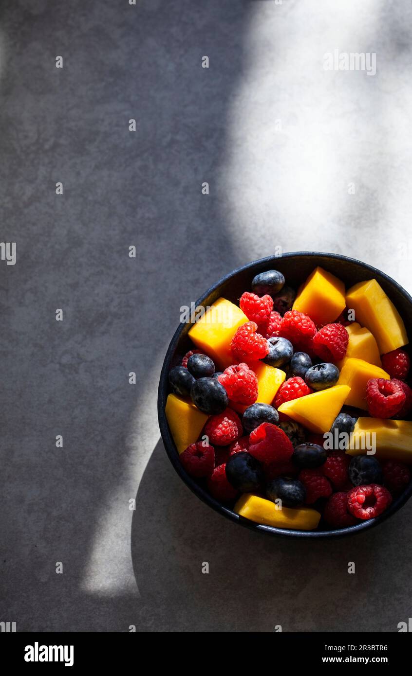 Colourful fruit salad with pieces of mango, raspberries and blueberries ...