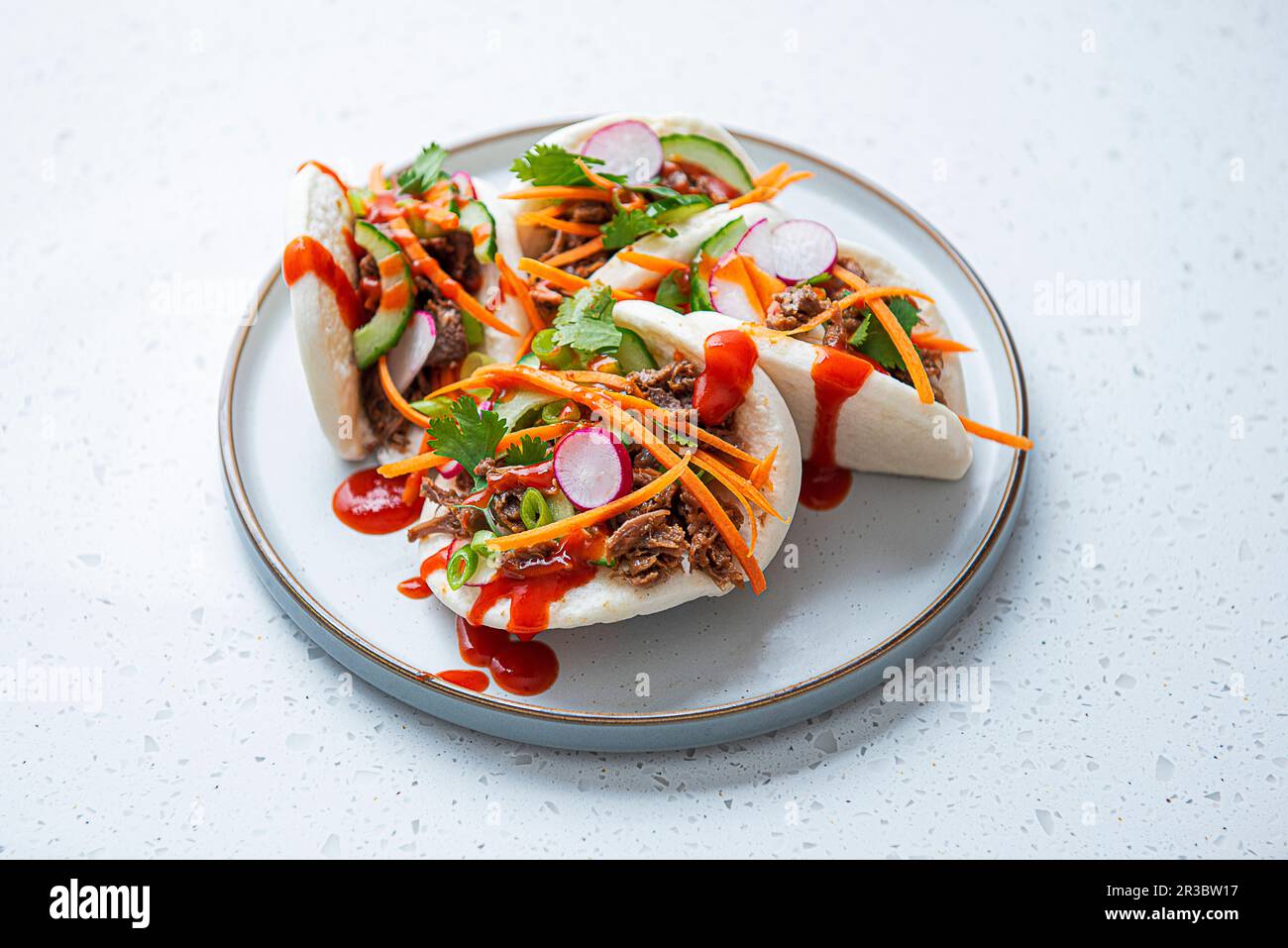 Steamed bao buns with spiced jackfruit, vegetables and siracha sauce ...