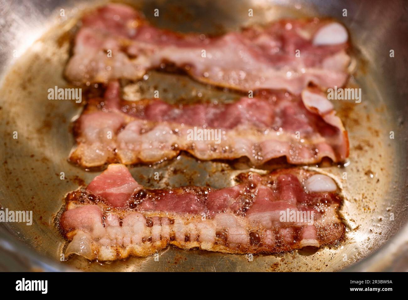 Frying bacon in a pan Stock Photo - Alamy