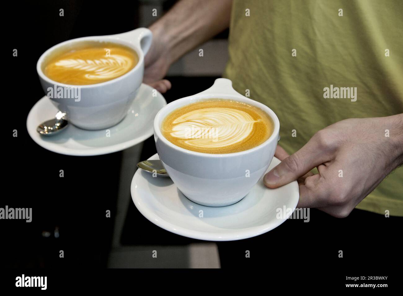Male barista holding two latte coffees with latte art Stock Photo - Alamy