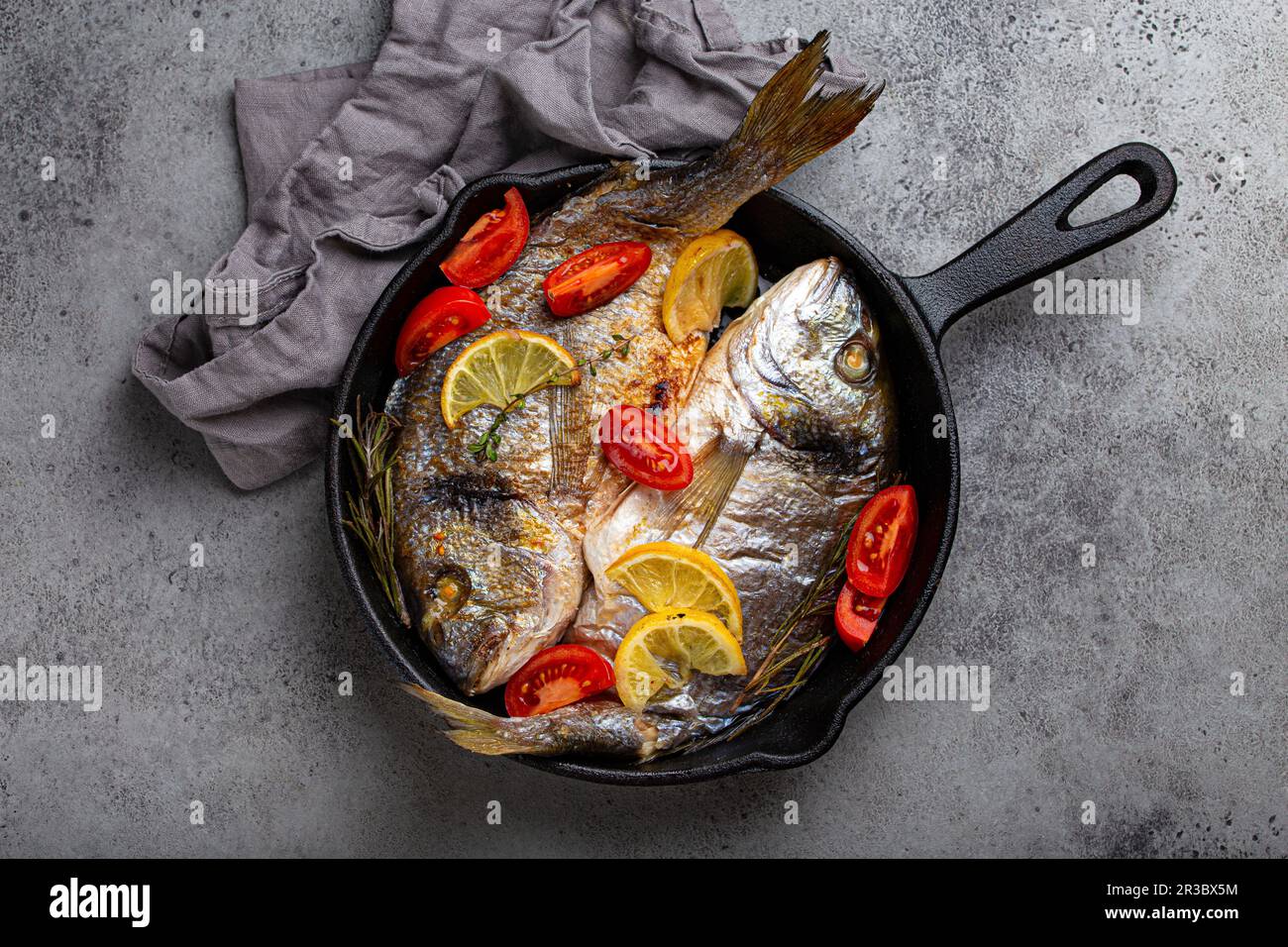 Roasted sea bream with lemon, tomatoes and herbs in pan Stock Photo - Alamy