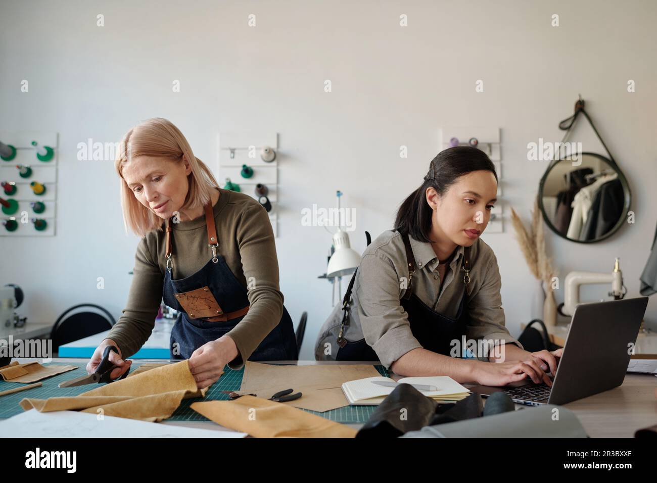 Young serious female leatherworker communicating with online clients ...