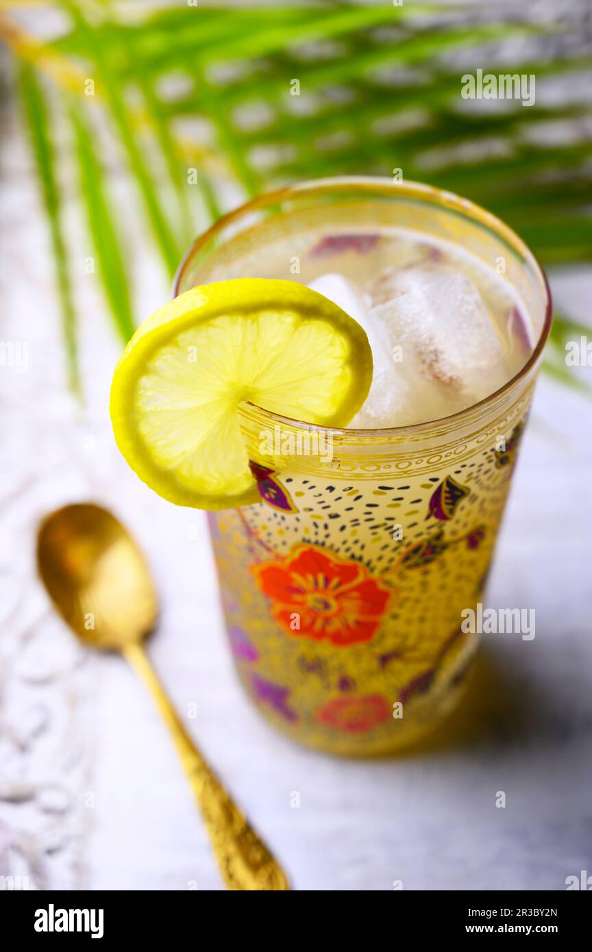 Spiked lemonade cocktail in a painted floral glass with a lemon slice garnish Stock Photo - Alamy
