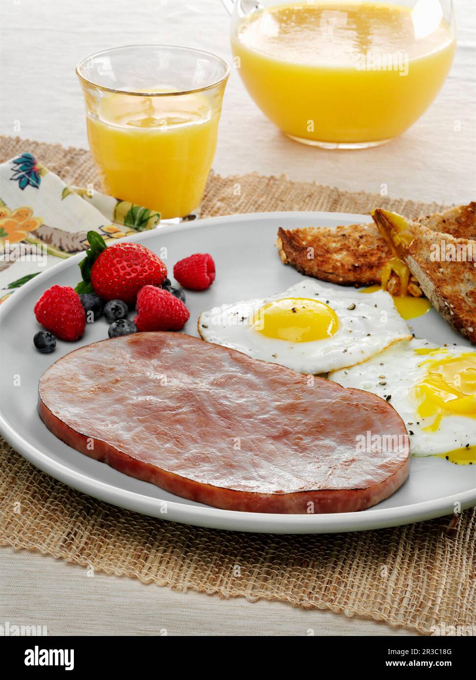 Boneless ham steak breakfast with fried eggs and whole grain toast ...
