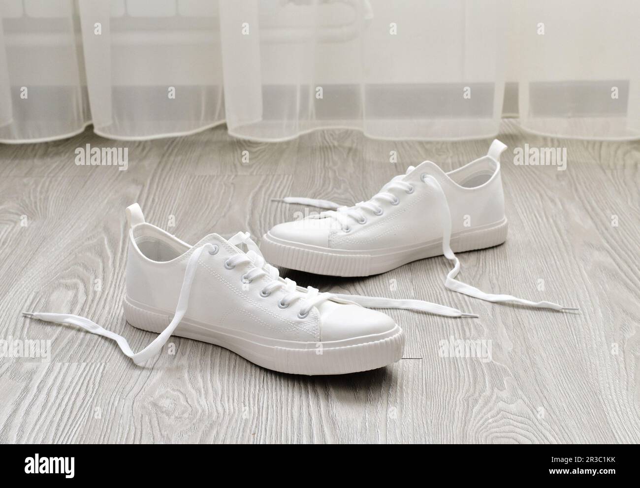 White sneakers with untied laces are on the floor Stock Photo - Alamy
