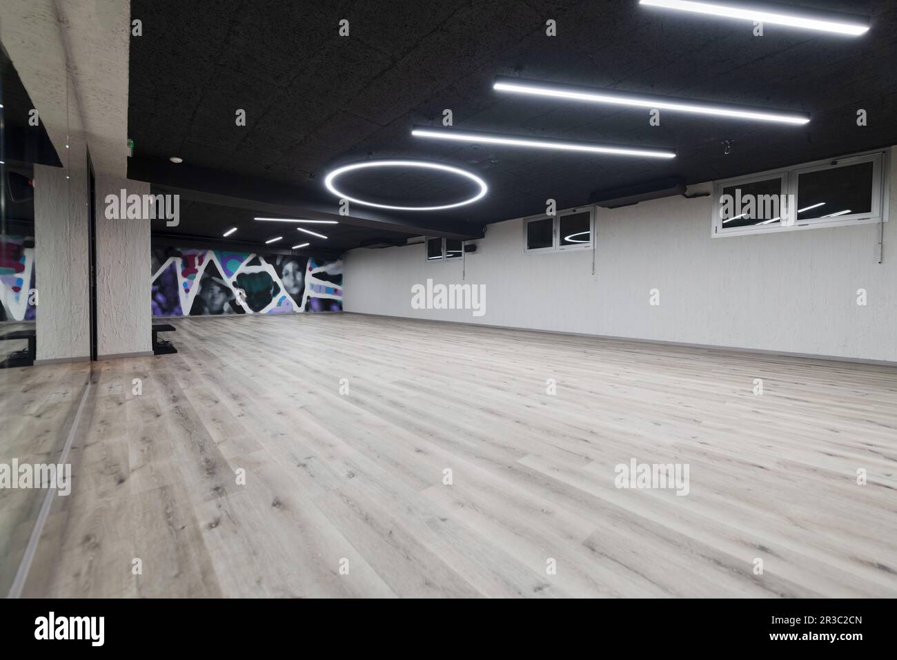An empty dance hall with a glass wall adorned with decorative graffiti ...