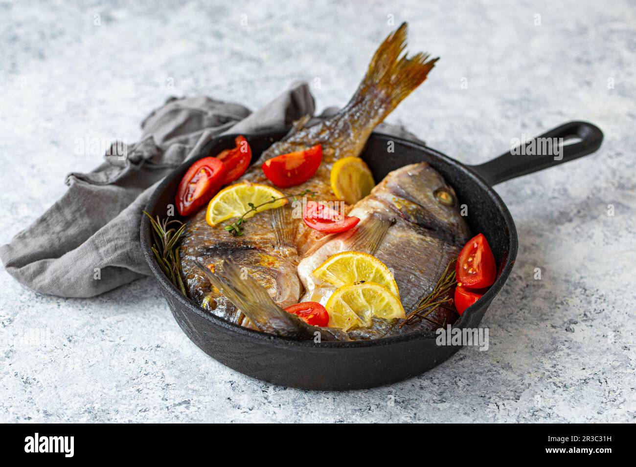Roasted sea bream with lemon, herbs and tomatoes in cast iron skillet ...