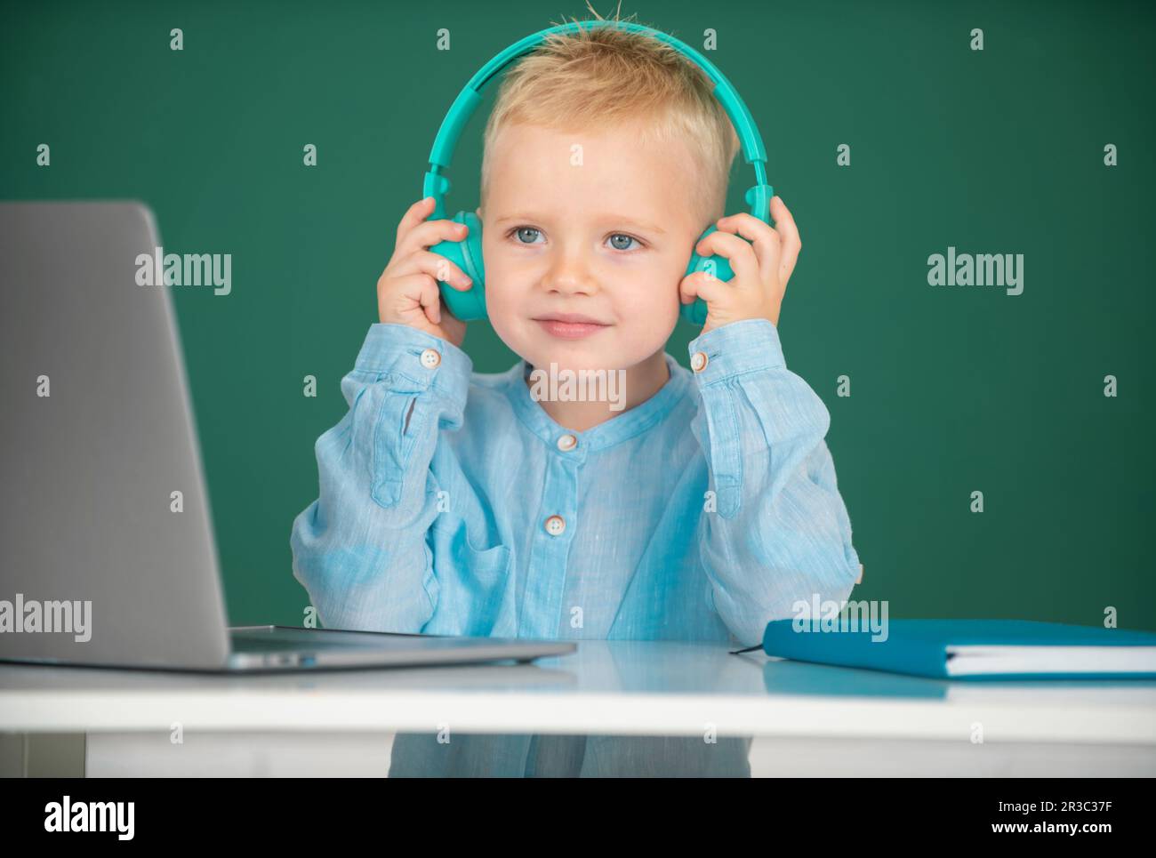Cute boy wearing headphones, study with laptop in classroom, listening ...
