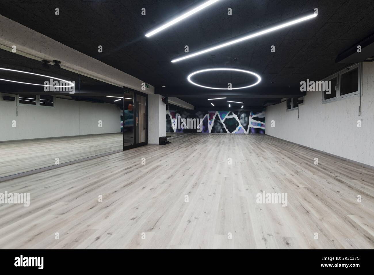 An empty dance hall with a glass wall adorned with decorative graffiti ...