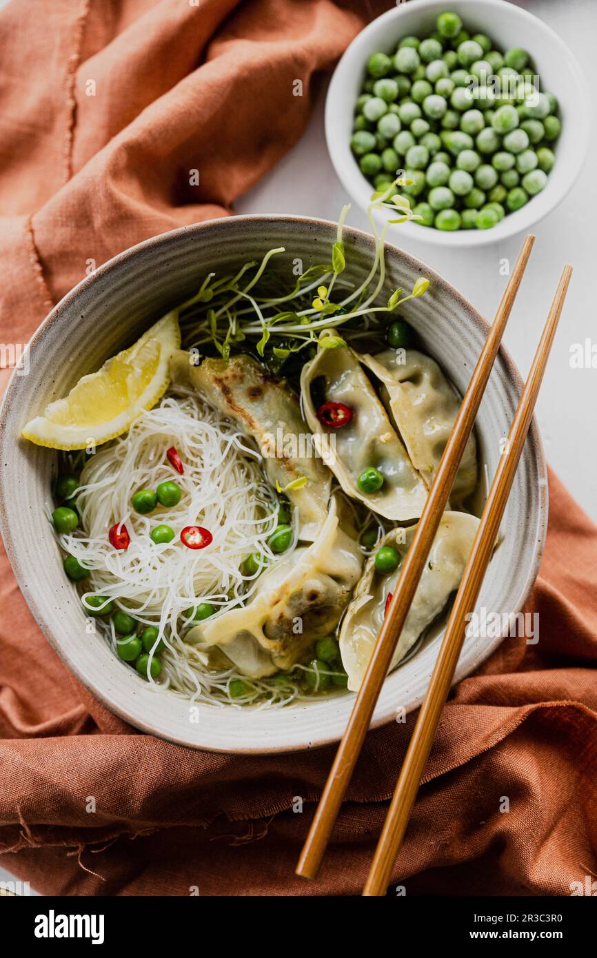 Gyoza, dumpling soup with thin rice noodles, broth, peas, chilli ...