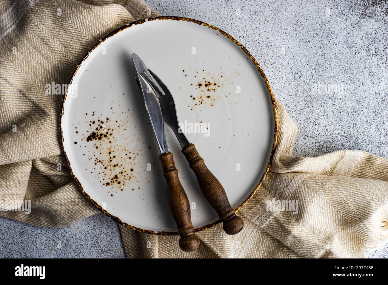 Rustic place setting with natural textile and plate on concrete ...