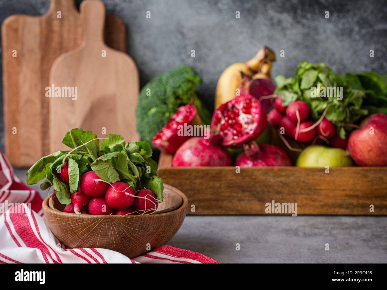 Bunch of fresh raw radish in wooden bowl, fresh fruit, greens ...