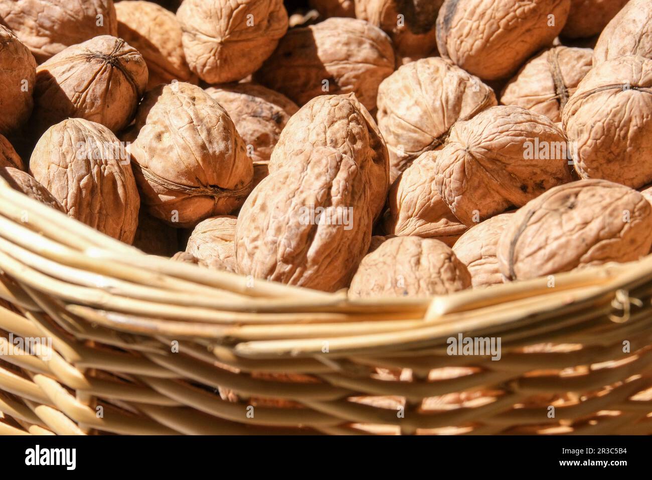 Close up organic whole unopened walnut shells inside wicker basket ...