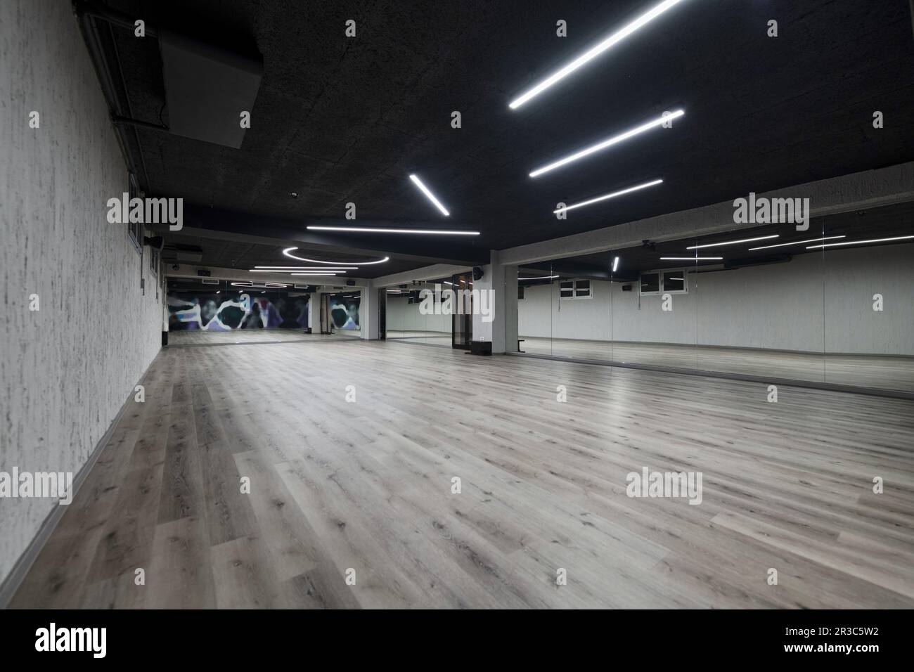 An empty dance hall with a glass wall adorned with decorative graffiti ...