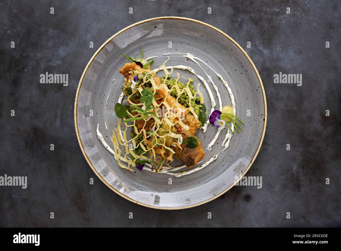A fine dining dish of fried fish, crushed peas and potato lattice Stock ...