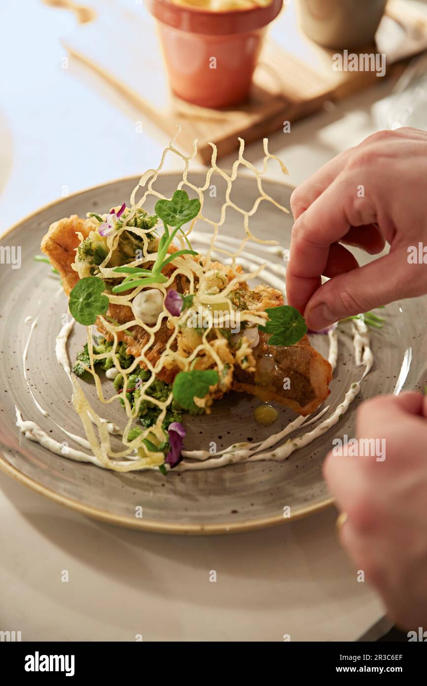 Adding the finishing touches to a fine dining dish of fried fish ...