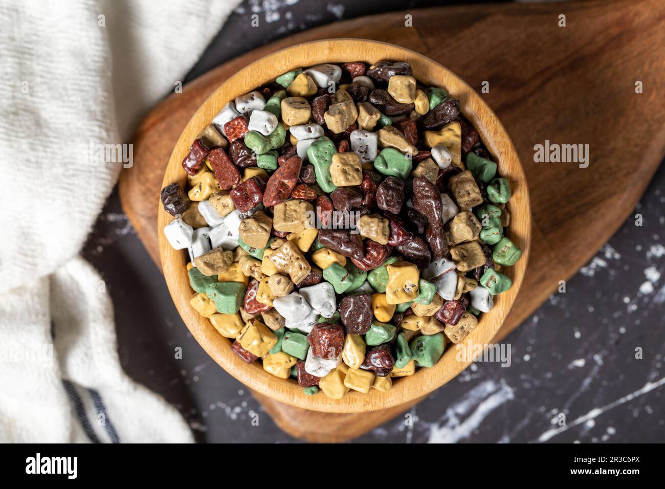 Colorful chocolate candy stones. Stone chocolate dragee in wooden bowl ...