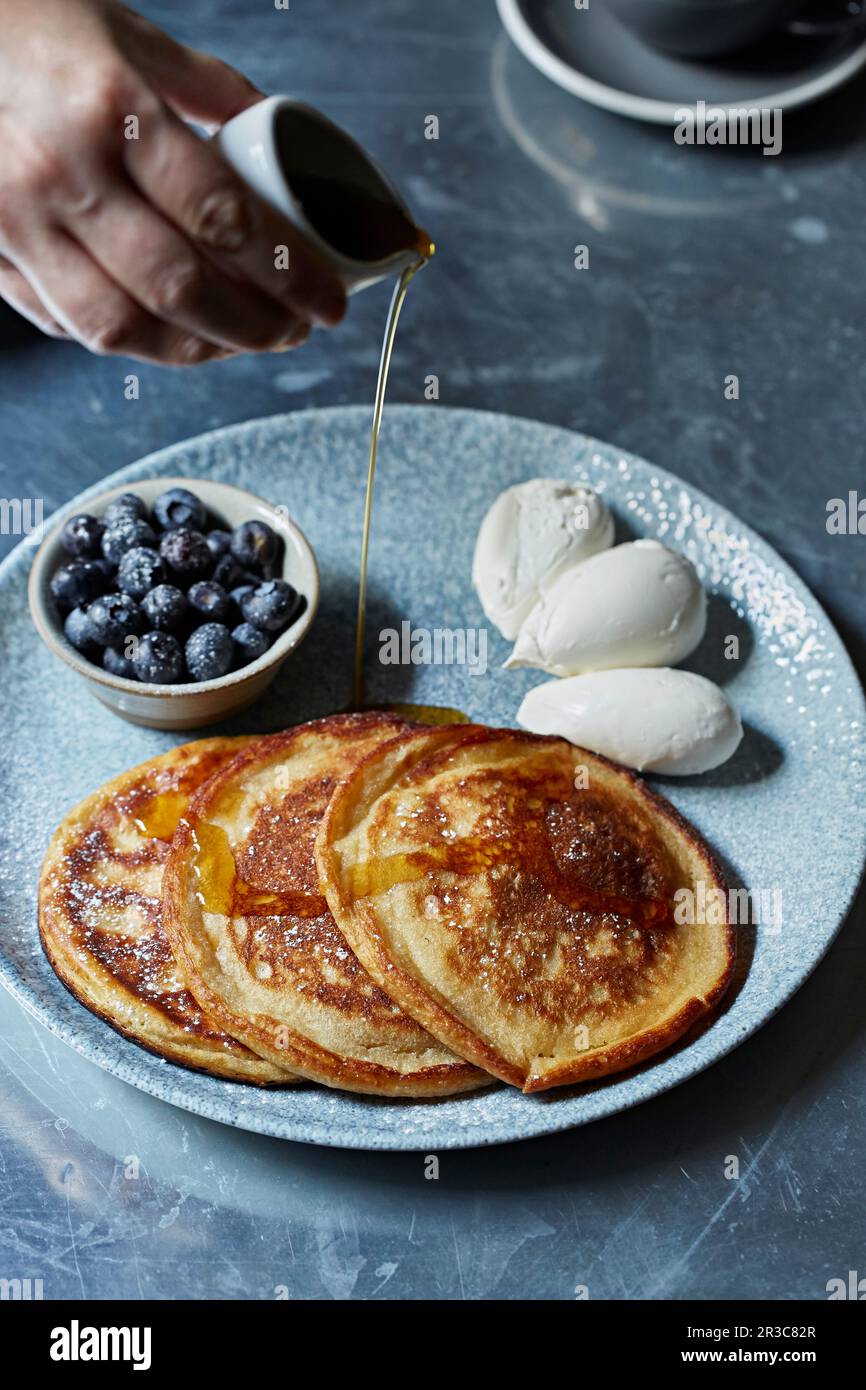 Maple syrup being poured on pancakes Stock Photo - Alamy