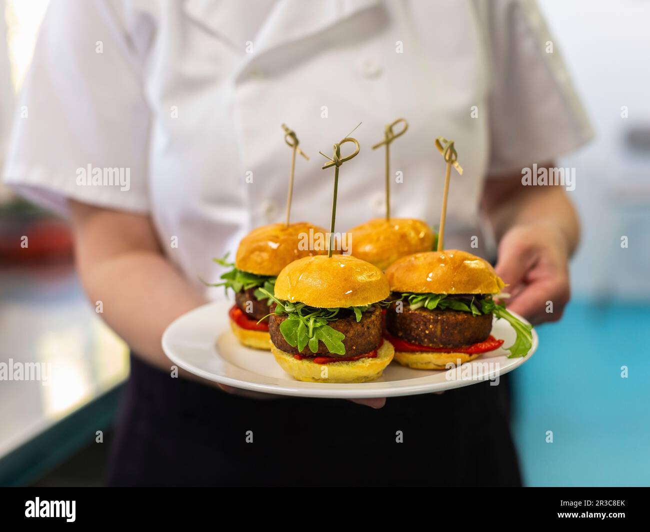 Waiter serves four mini veggie burgers Stock Photo - Alamy