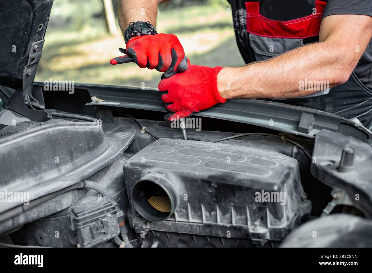 An auto mechanic opens the air filter housing of an internal combustion ...