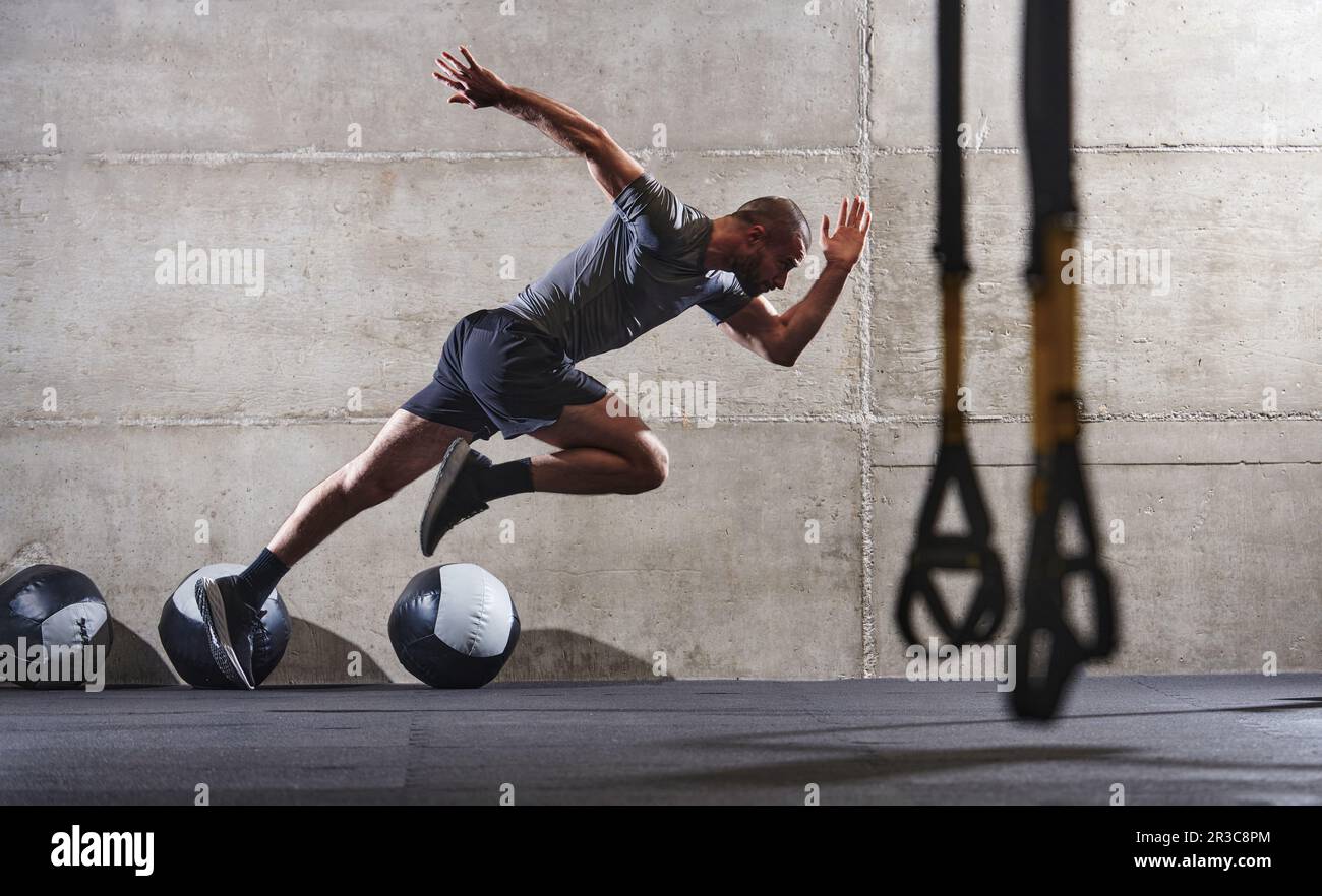 A muscular man captured in air as he jumps in a modern gym, showcasing ...