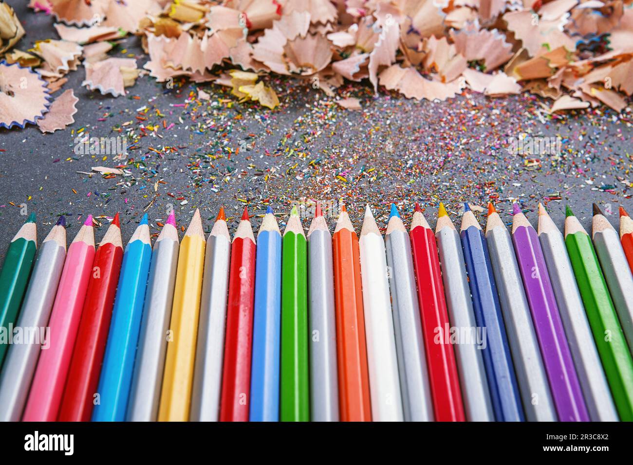 Close up shot of colored pencil crayons and pencil crayons shavings on dark background ...