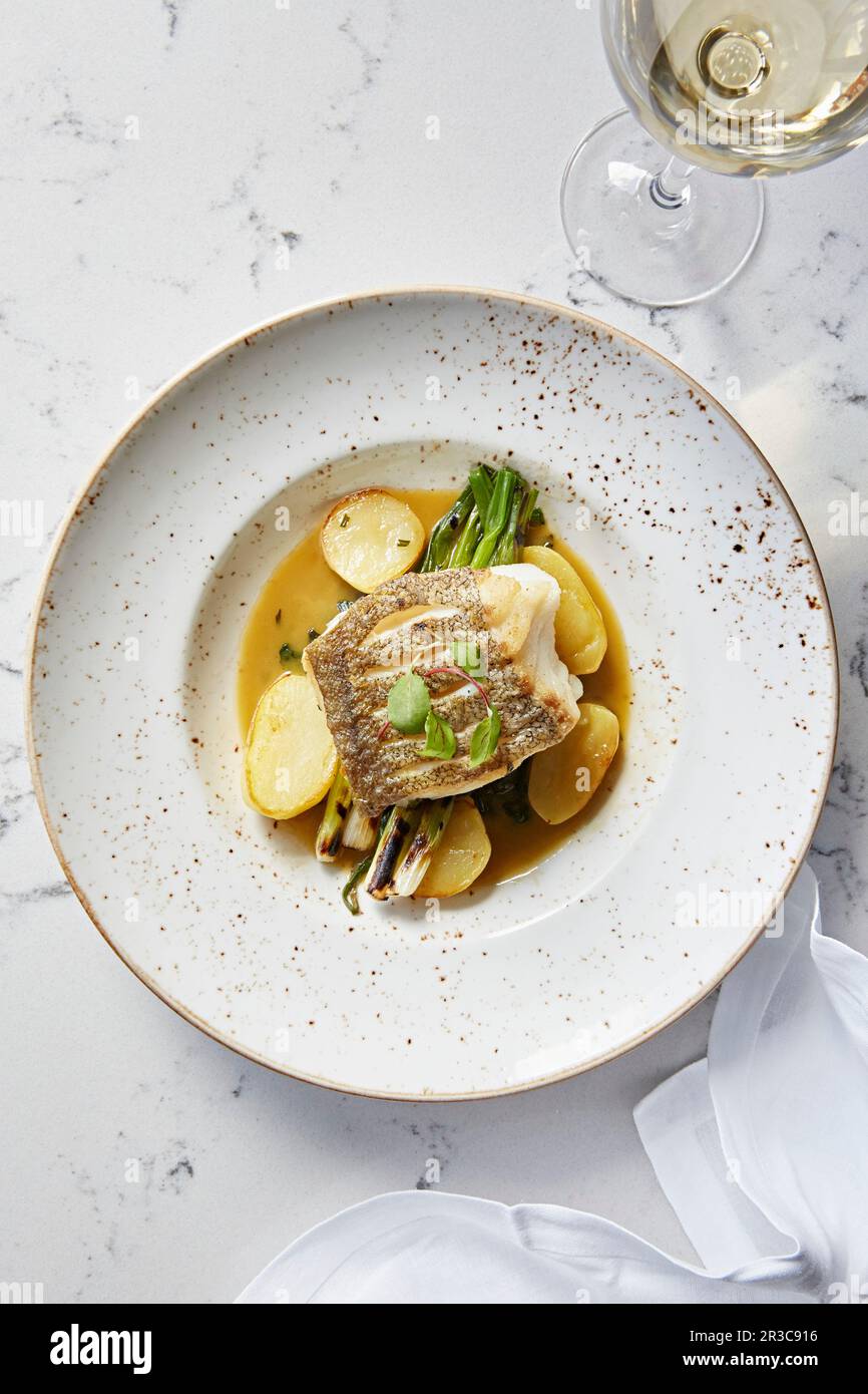 Pan seared fish with potatoes and asparagus served with white wine ...