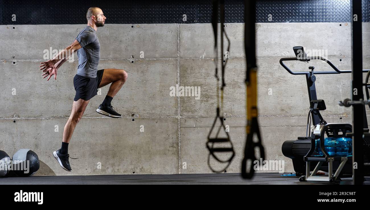 A muscular man captured in air as he jumps in a modern gym, showcasing ...