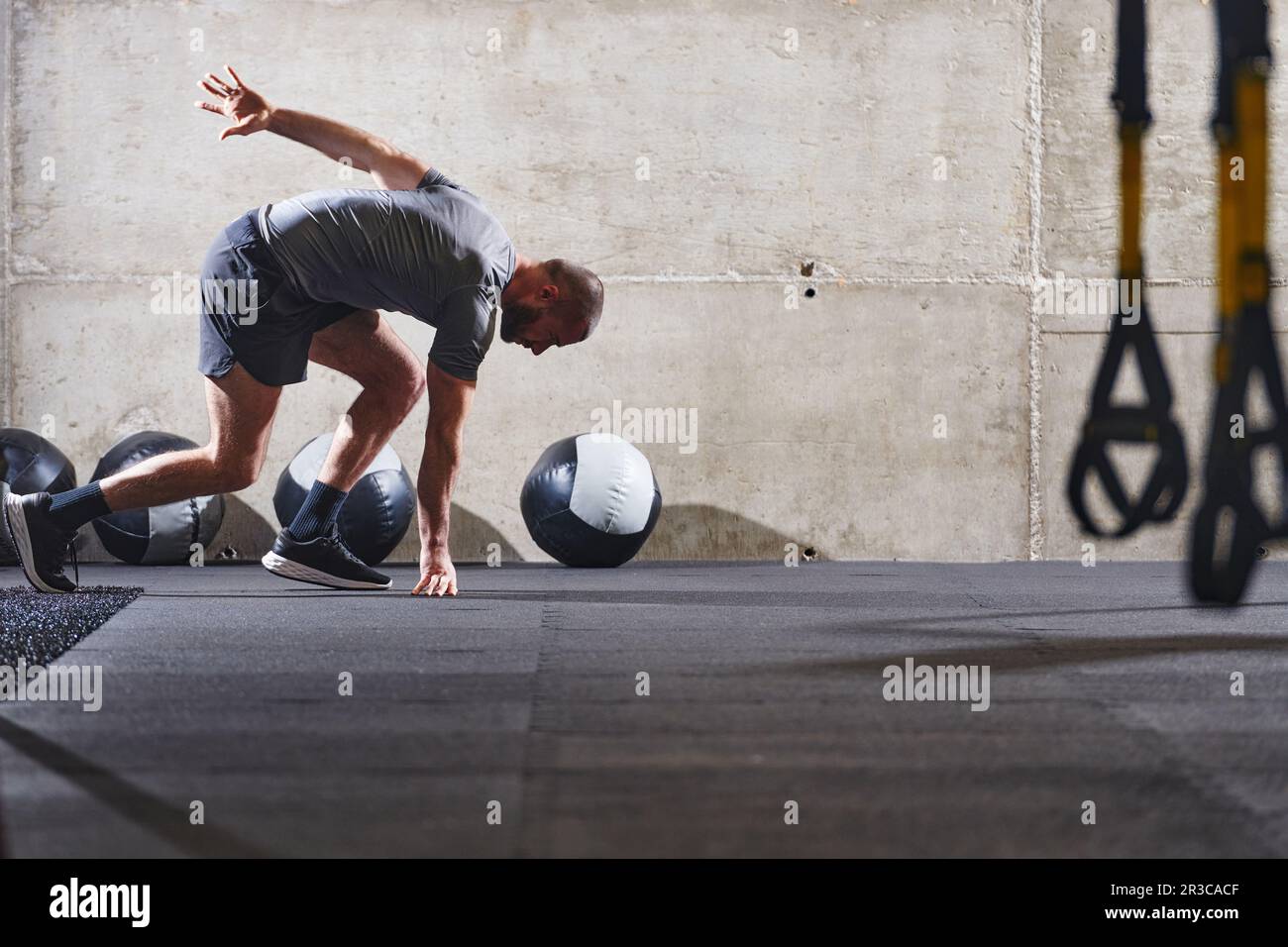 A muscular man captured in air as he jumps in a modern gym, showcasing ...