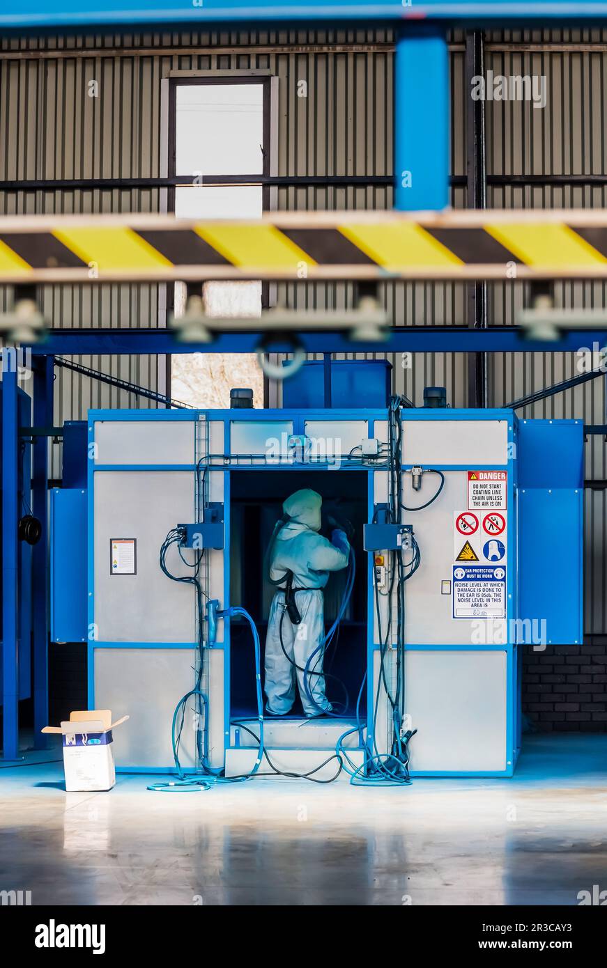 Tradesman working in a painting booth, Man paining industrial equipment ...
