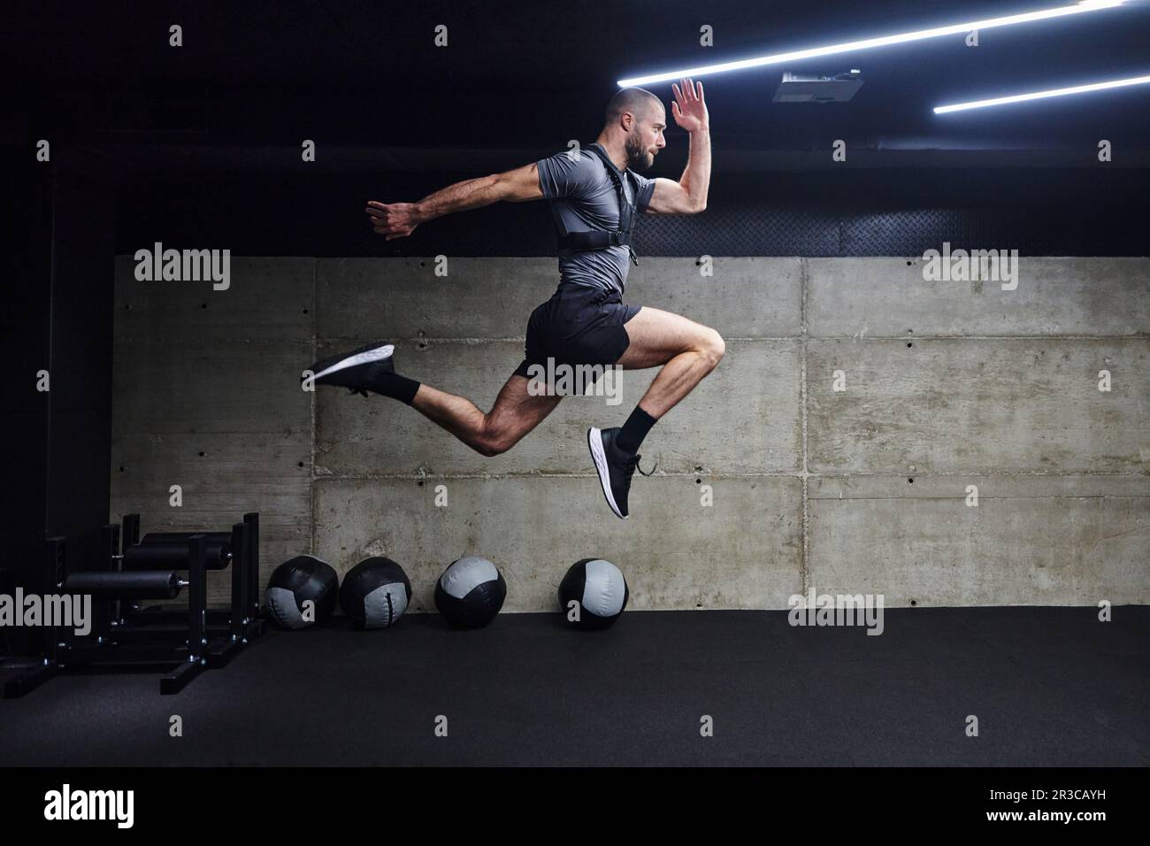 A muscular man captured in air as he jumps in a modern gym, showcasing ...