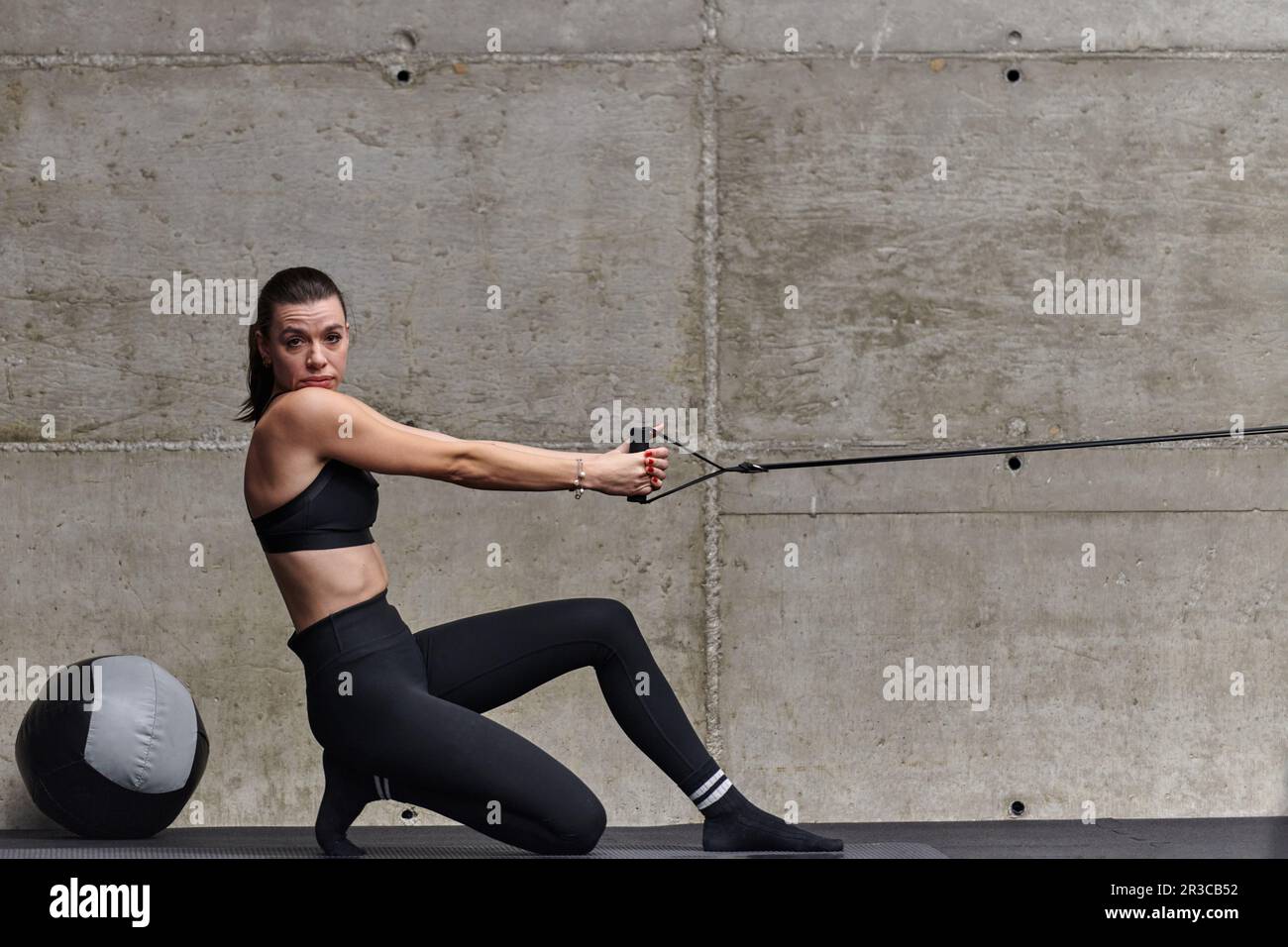 A fit woman in a modern gym performs arm exercises with determination ...
