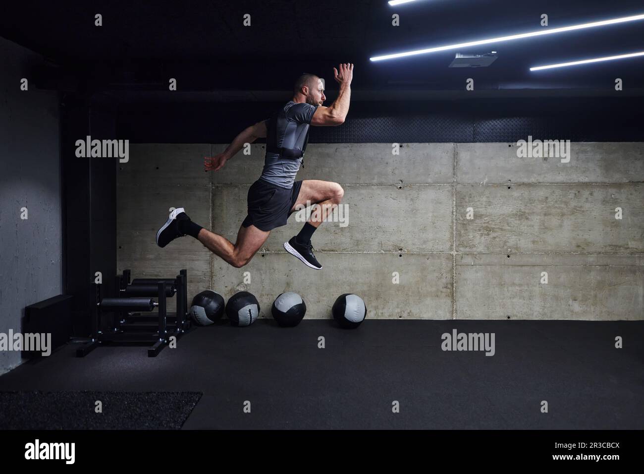 A muscular man captured in air as he jumps in a modern gym, showcasing ...