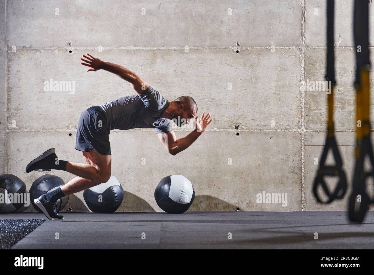 A muscular man captured in air as he jumps in a modern gym, showcasing ...