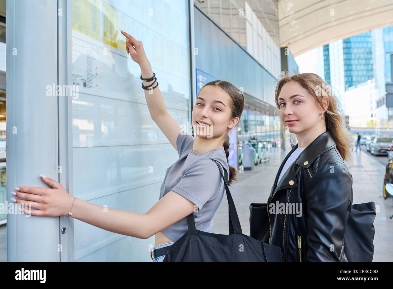 Two young females reading the transport timetable on the scoreboard ...