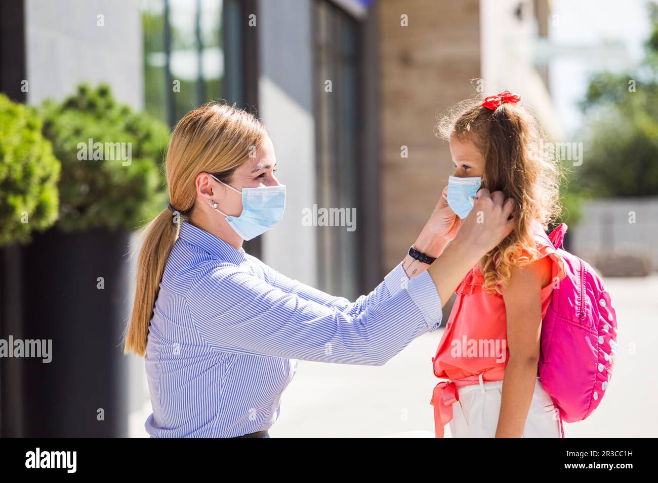 Mom puts a protective mask on her daughter before start school Stock Photo - Alamy