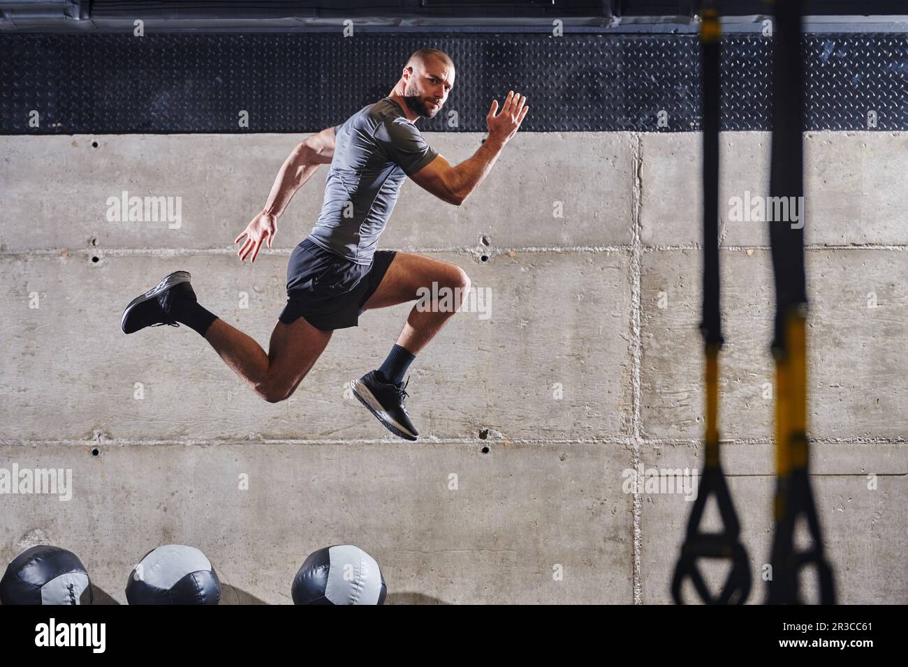 A muscular man captured in air as he jumps in a modern gym, showcasing ...