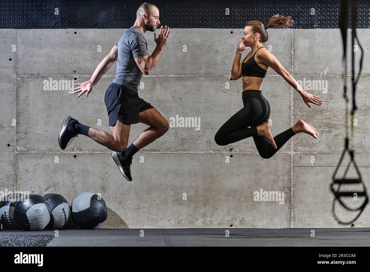 A fit couple exercising various types of jumps in a modern gym ... A fit couple exercising various types of jumps in a modern gym ...