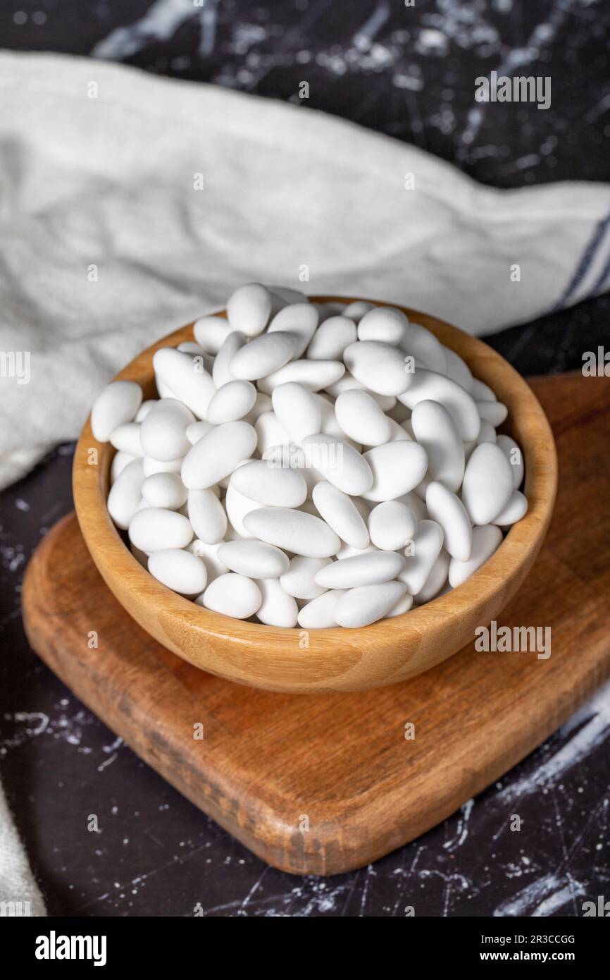 Almond candy. Sugar coated almond candy in wooden bowl on dark ...
