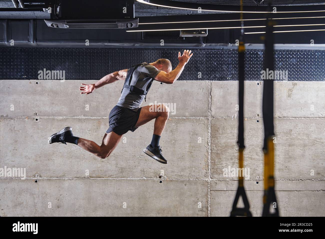 A muscular man captured in air as he jumps in a modern gym, showcasing ...