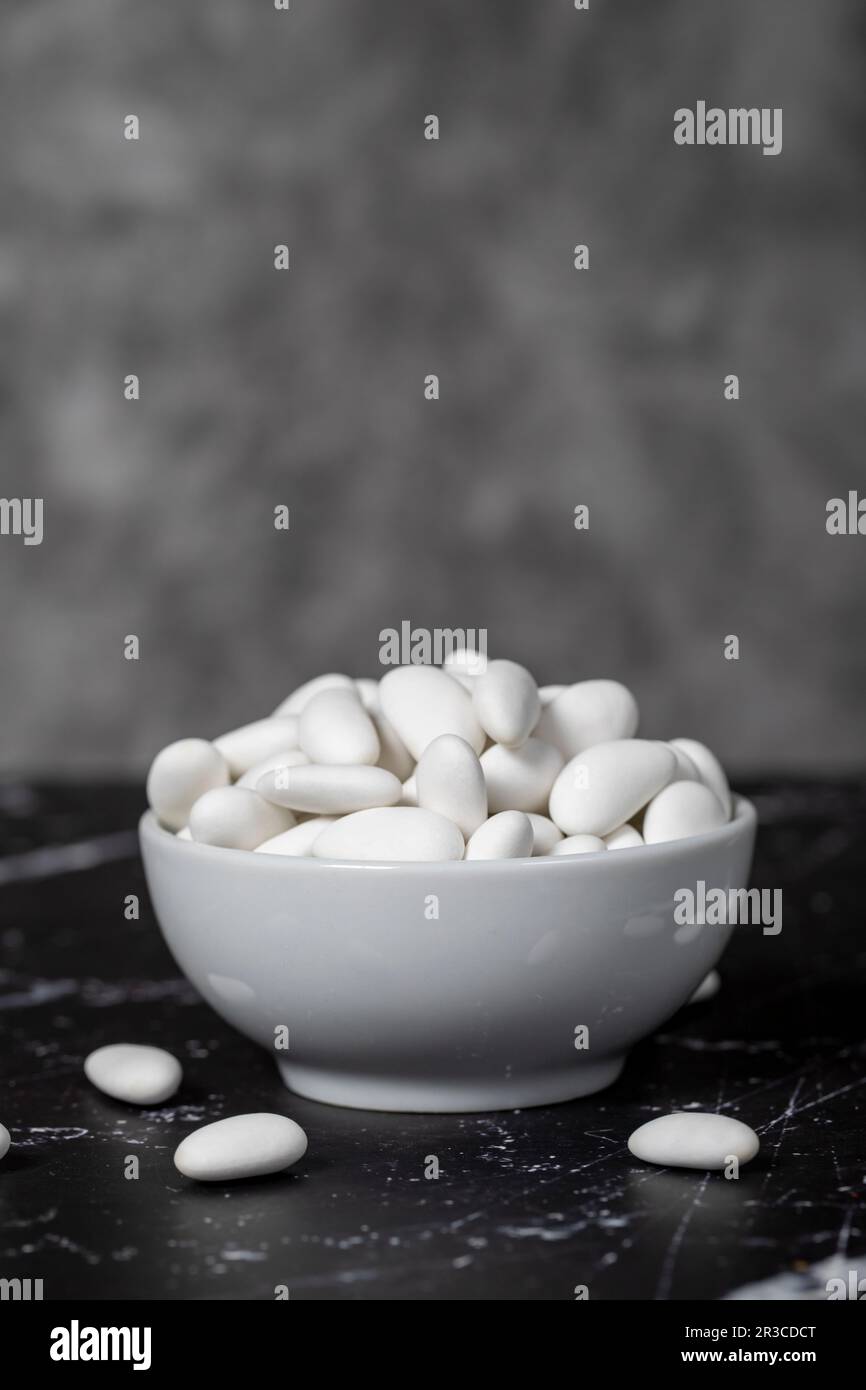 Almond candy. Sugar coated almond candy in ceramic bowl on dark ...