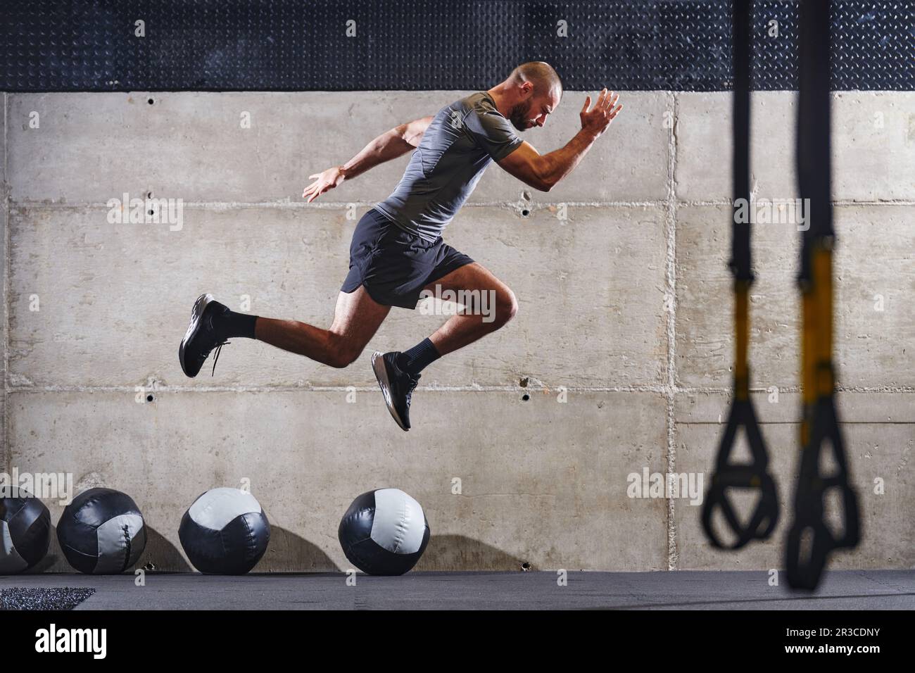 A muscular man captured in air as he jumps in a modern gym, showcasing ...