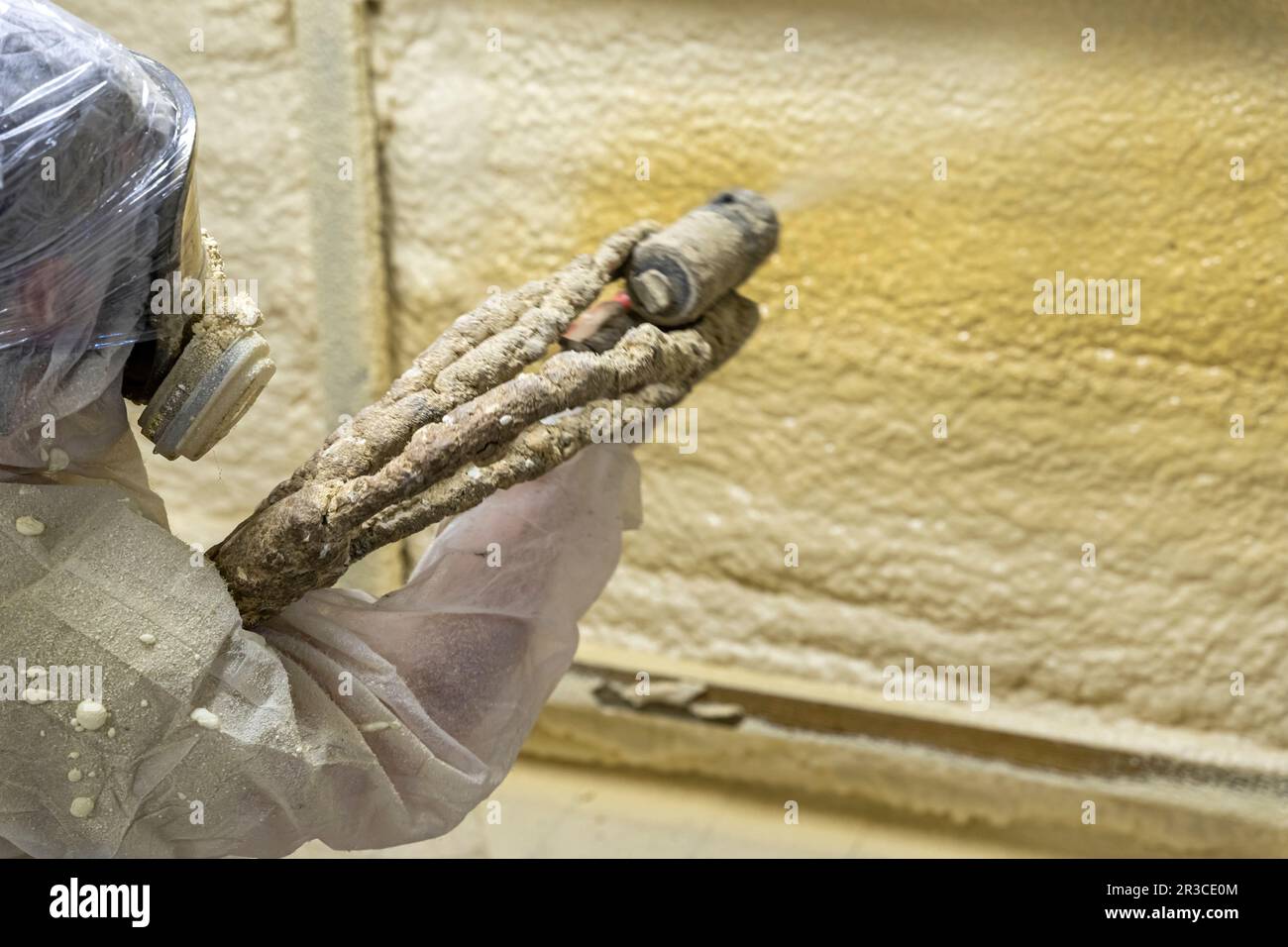 worker in a protective suit insulates the walls with polyurethane foam ...